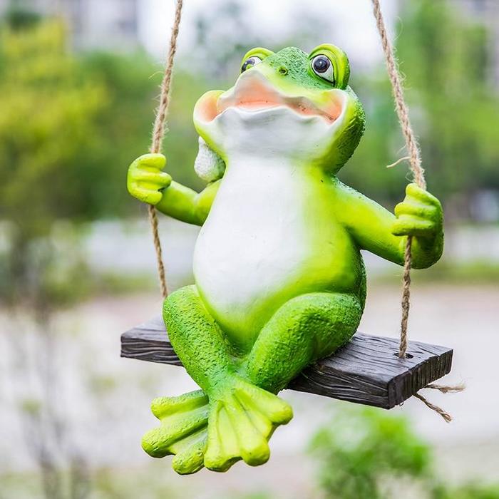 Frosch auf der Schaukel. Lustige und schöne Gartenfigur als ...